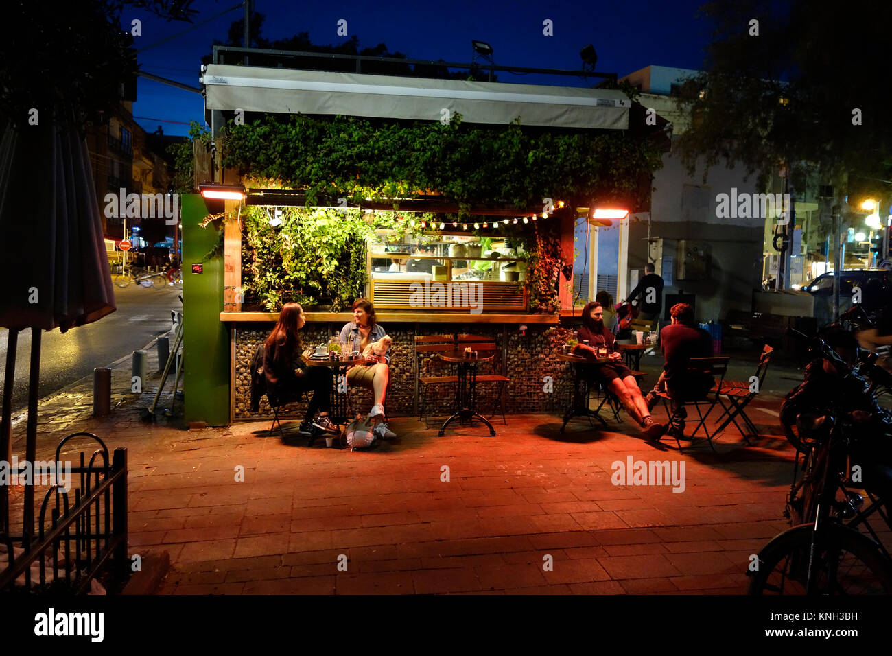 People sitting in a coffee kiosk in the junction of Dizengoff street ...