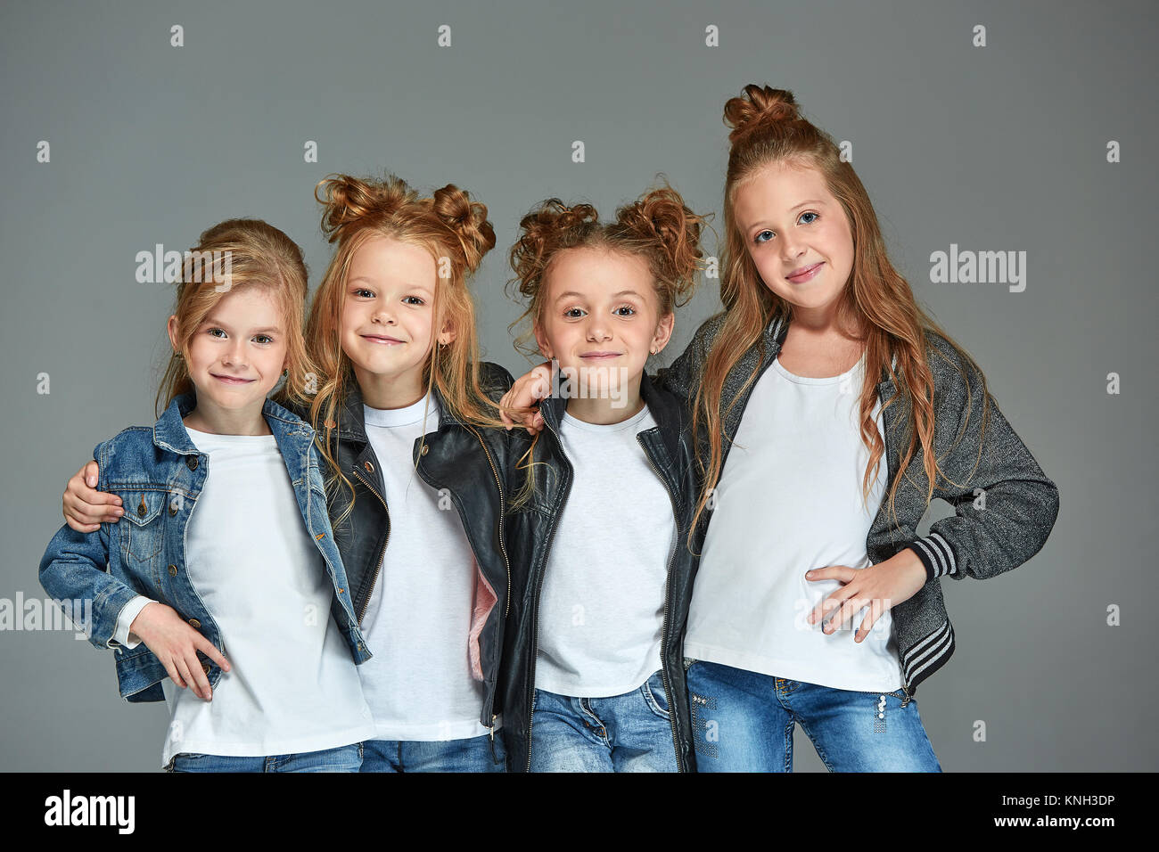Young girls posing together on gray studio background Stock Photo - Alamy