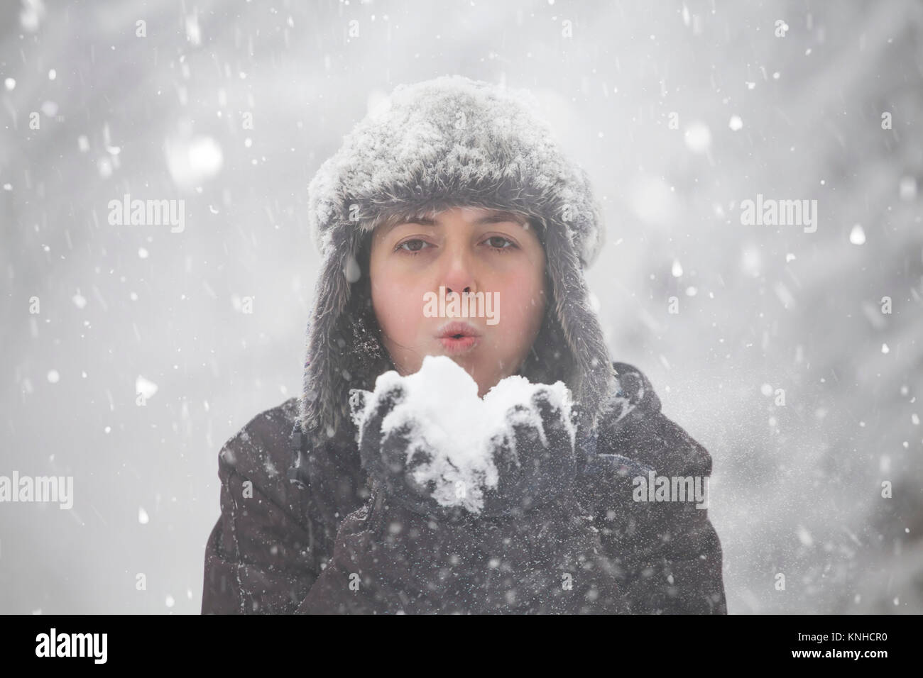 Happy woman blowing snow in winter forest. Girl having fun outdoor in ...