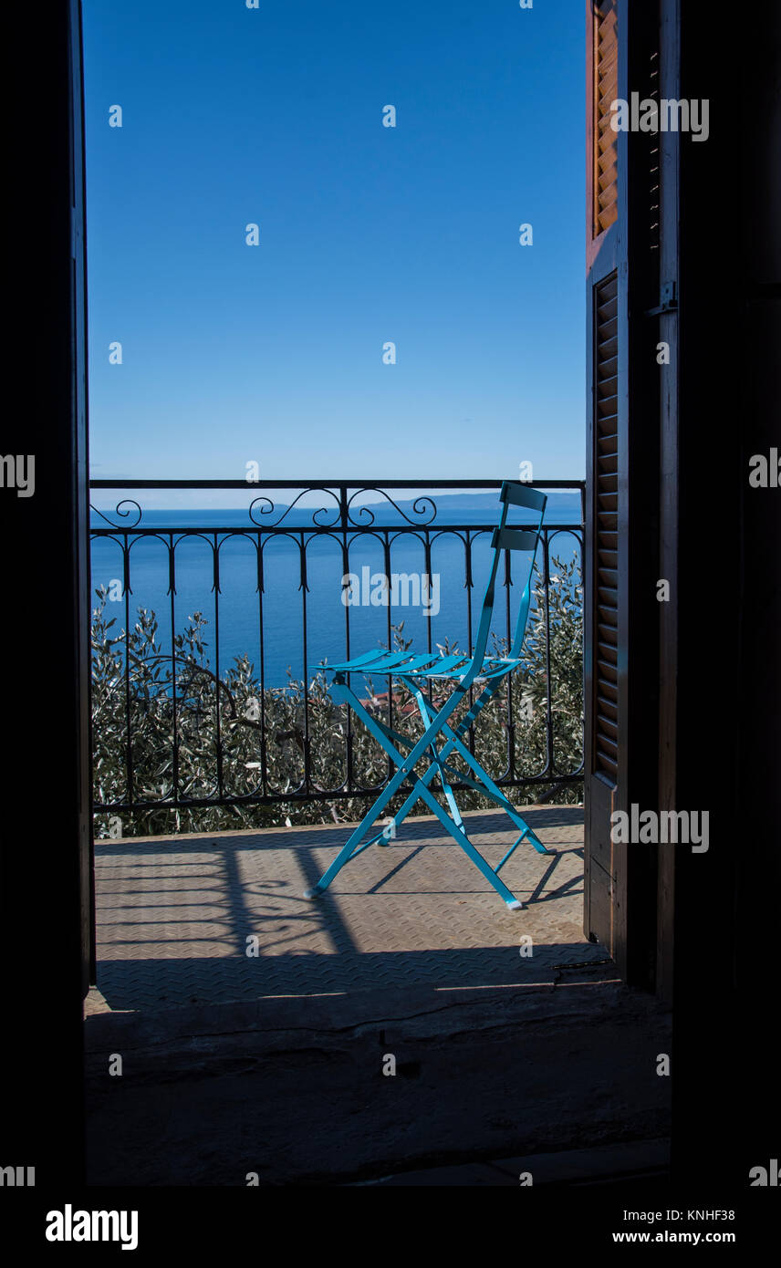 Blue chair on a balcony looking out to a warm sea, Kardamyli, west ...