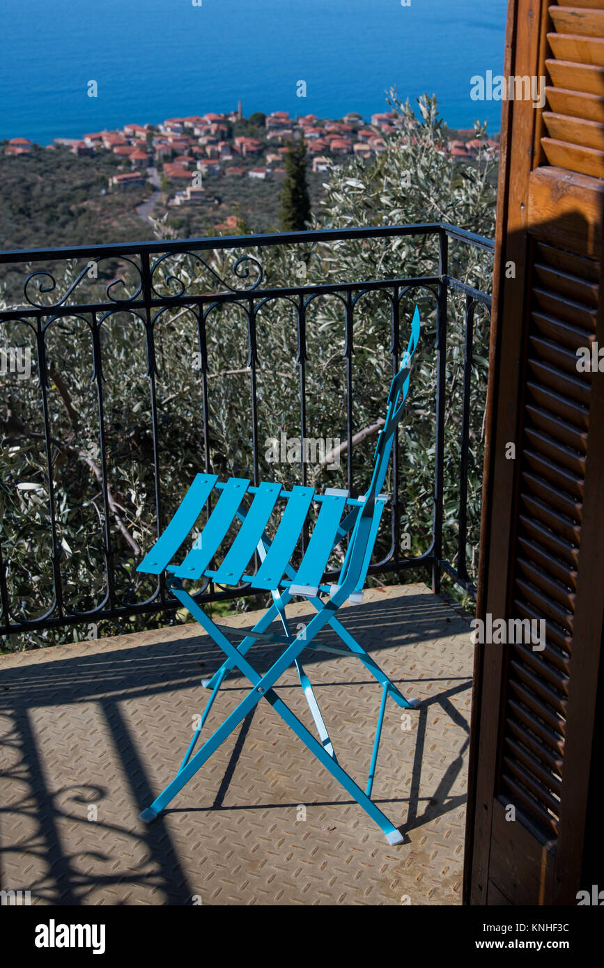Blue chair on a balcony looking out to a warm sea, Kardamyli, west ...