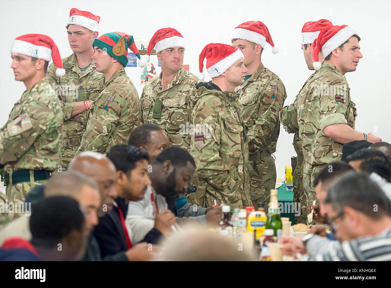 U.S. soldiers wearing Santa Claus hats wait in line for a holiday meal ...