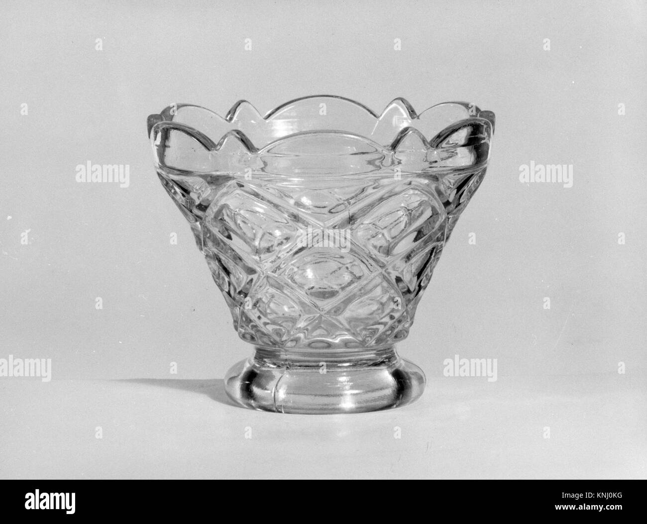 This footed bowl, made from pressed glass, features a diamond ...