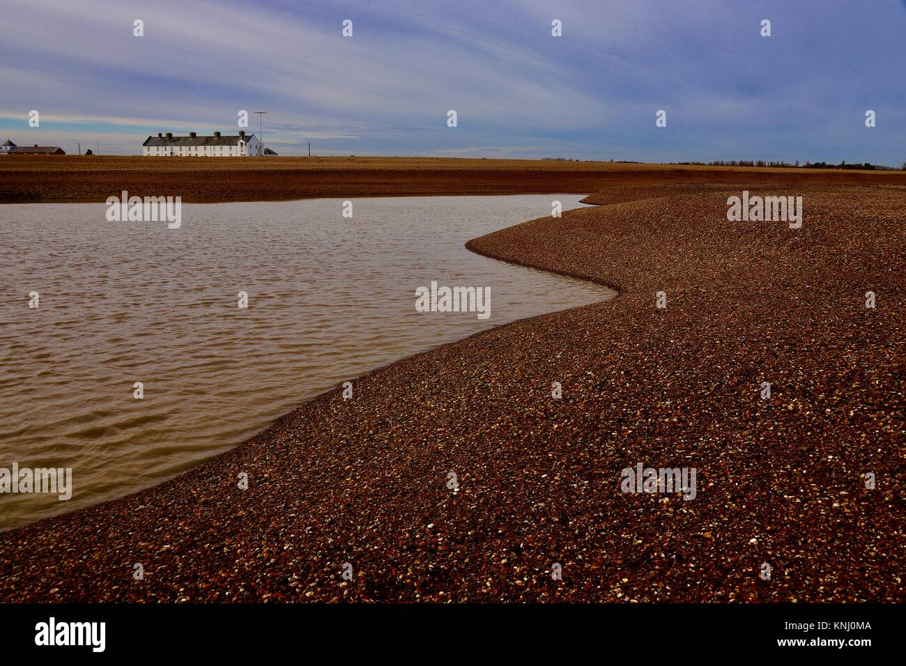 White cottages and curvy shingle banks around a salty lagoon at Shingle ...