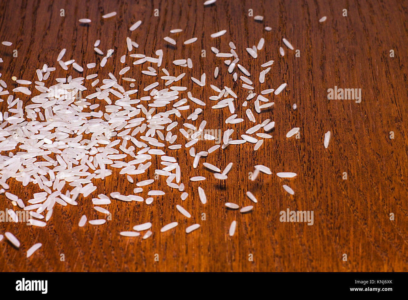 Grains of white rice are scattered on a wooden table Stock Photo - Alamy