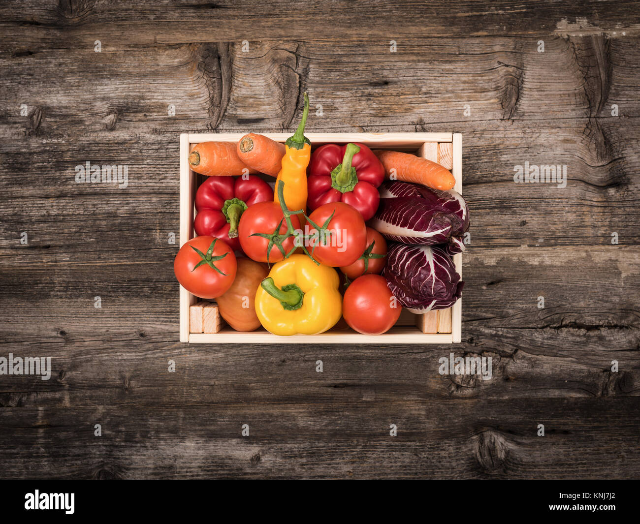 Fresh tasty red and yellow vegetables in wooden crates on a rustic ...