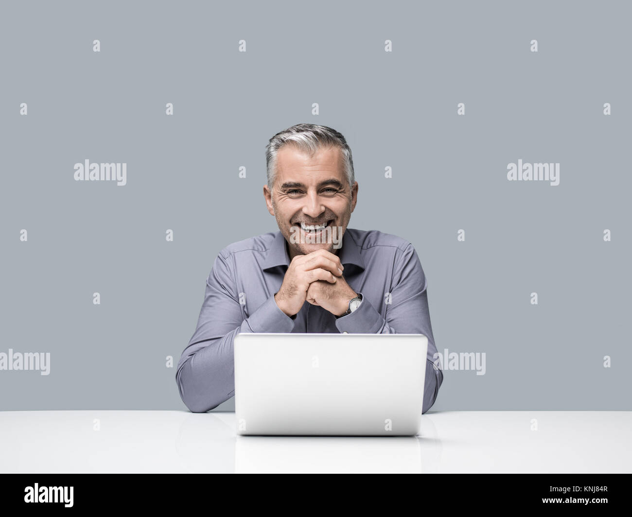 Confident successful smiling businessman sitting at office desk and ...