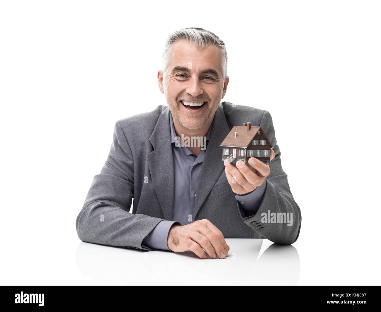 Smiling real estate agent holding a model house, housing and safe ...