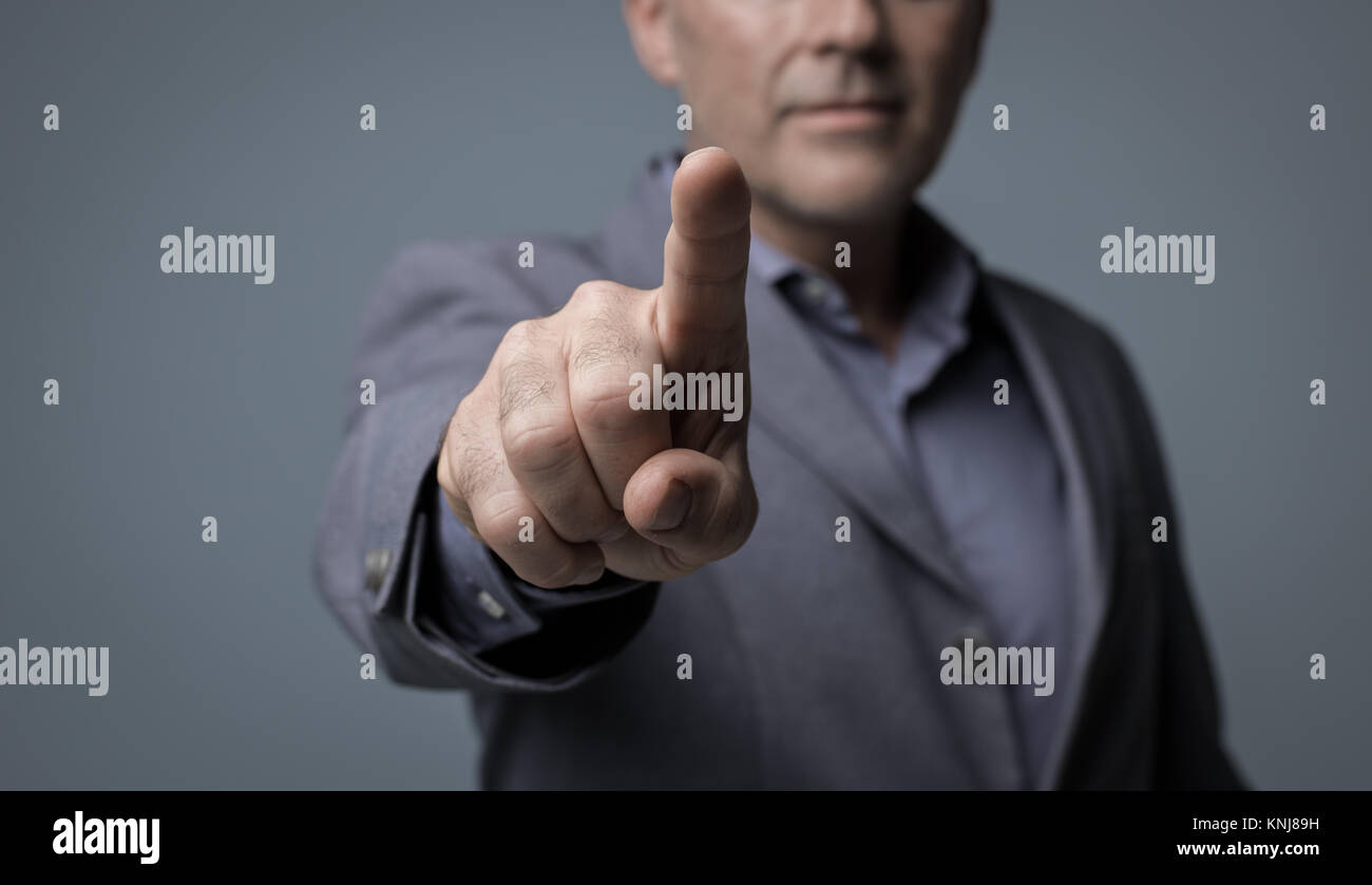 Businessman using a virtual interface and pointing at screen with his ...