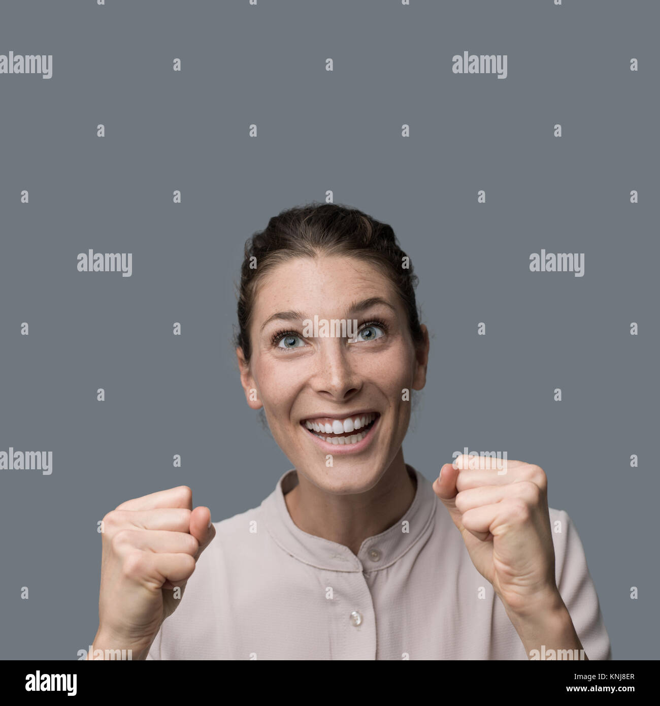 Cheerful excited winner woman with raised fists, she is smiling at ...