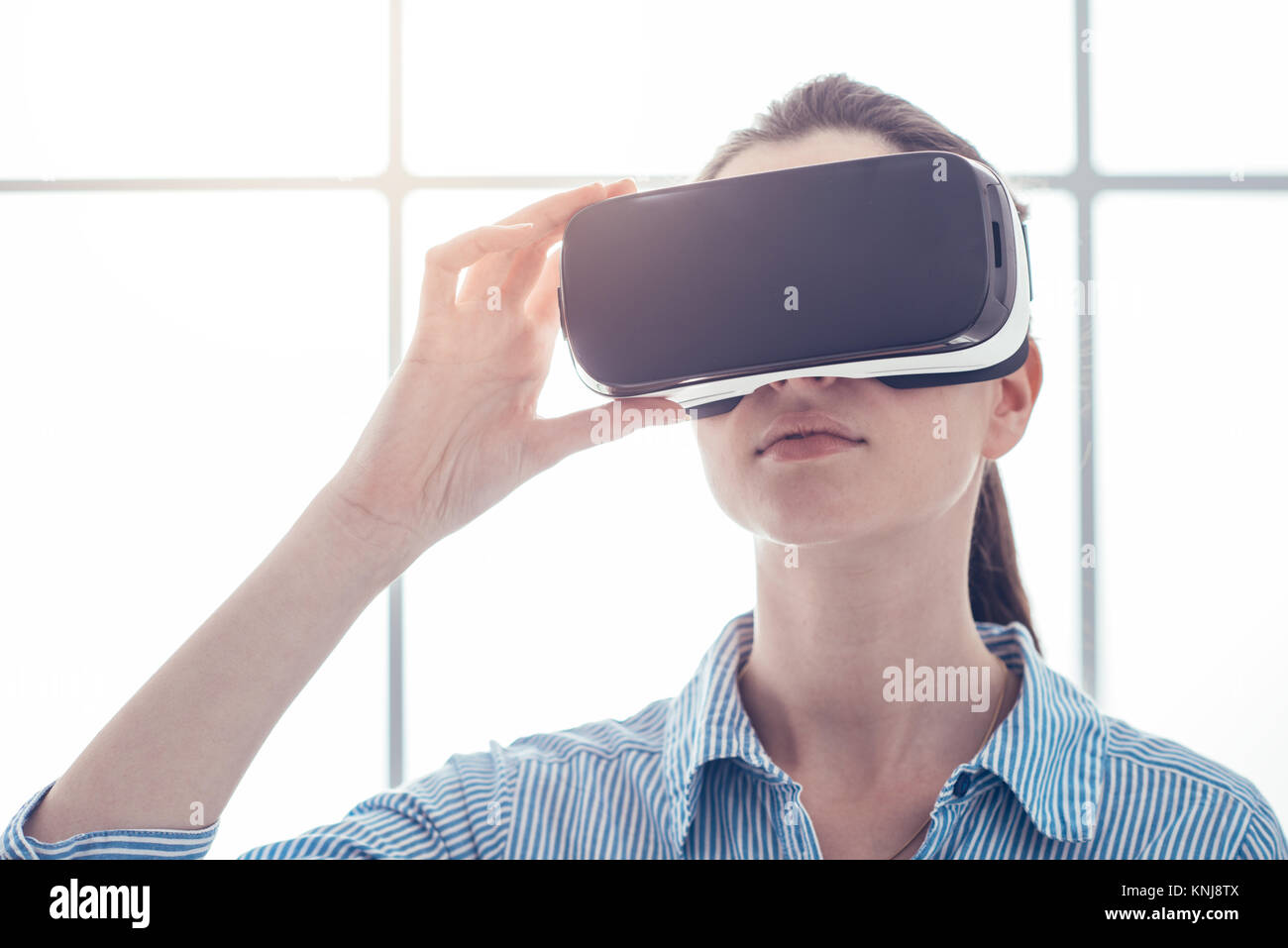 Young woman experiencing virtual reality, she is wearing a VR headset ...