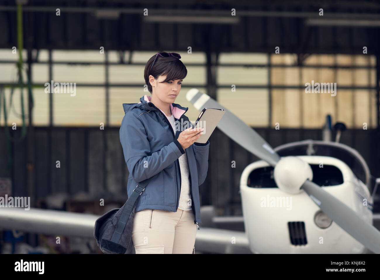 Confident female pilot in the hangar doing a pre-flight preparation ...