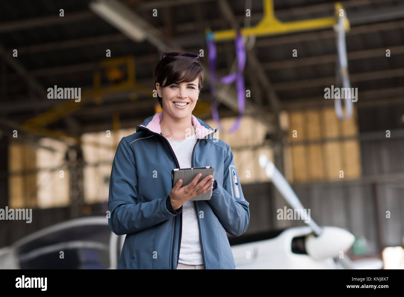 Smiling female pilot connecting with a digital tablet and using ...