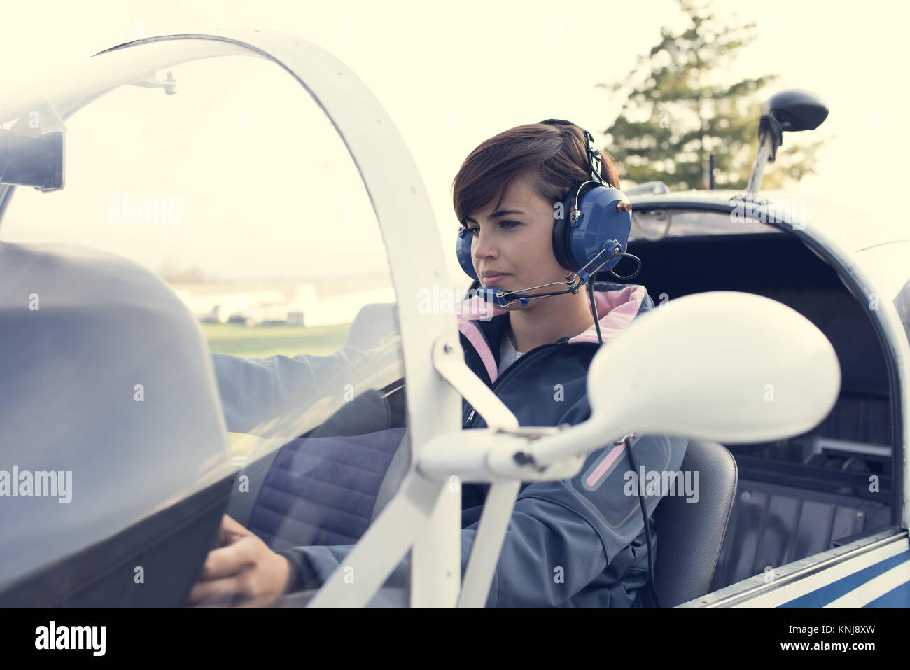 Smiling female pilot in the light aircraft cockpit, she is wearing ...
