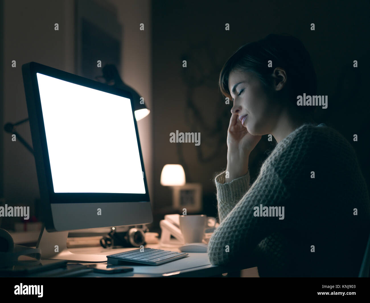 Tired young woman working with her computer late at night, she is ...