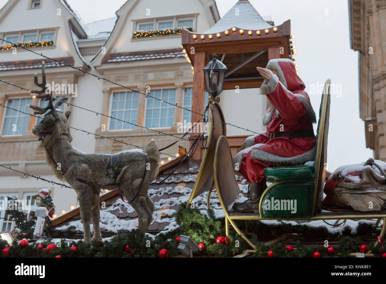A Santa Claus statue sits in a sled that is pulled by a reindeer on top ...