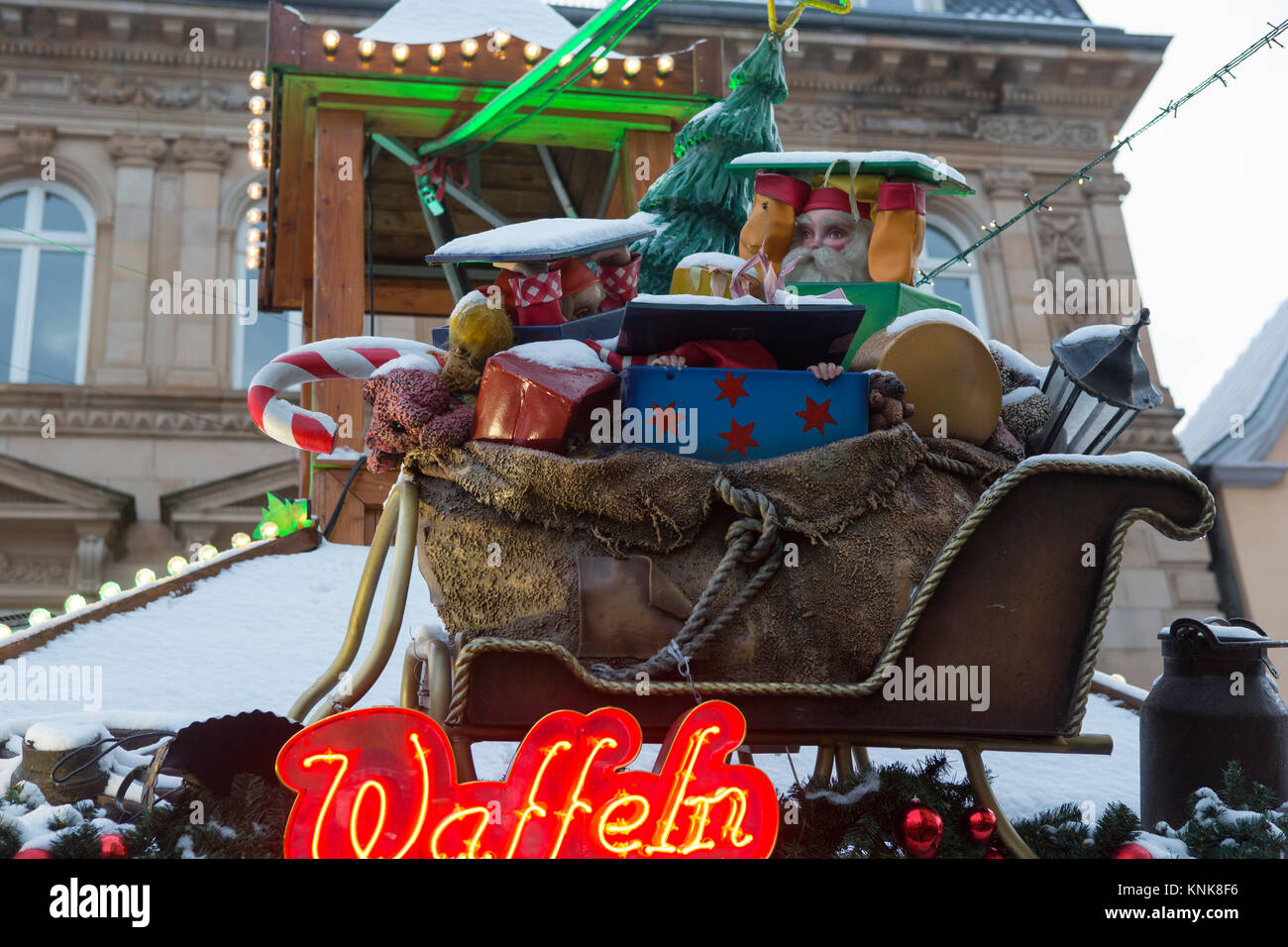 A sled wit presents stands on top of a stall. Statues of Santa Claus ...