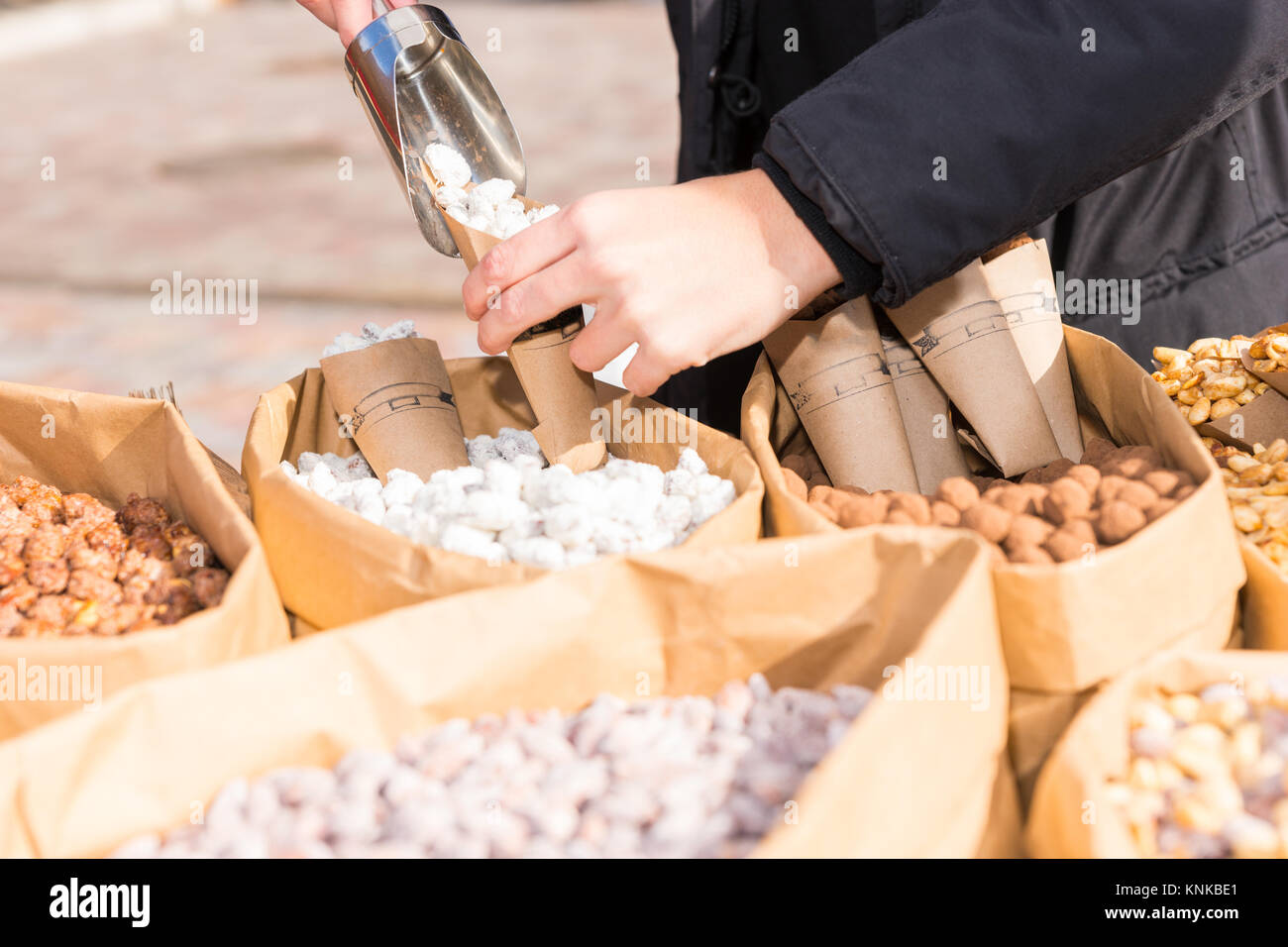 Unrecognizable female hands pour nuts into a paper cup outdoor on food ...