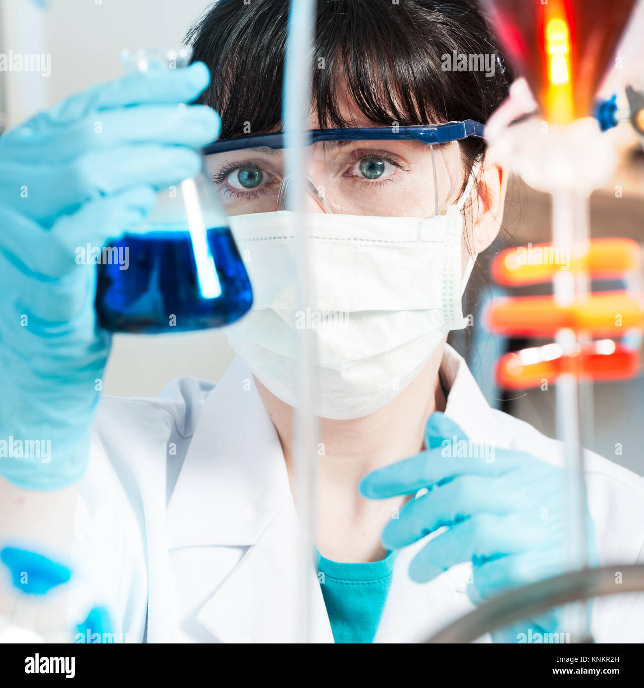 Young chemist in protective wear observes reaction in conical flask ...
