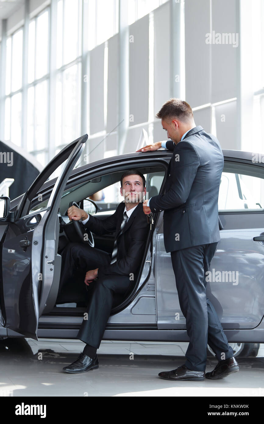 businessman receives from the Manager the keys,sitting behind the wheel ...