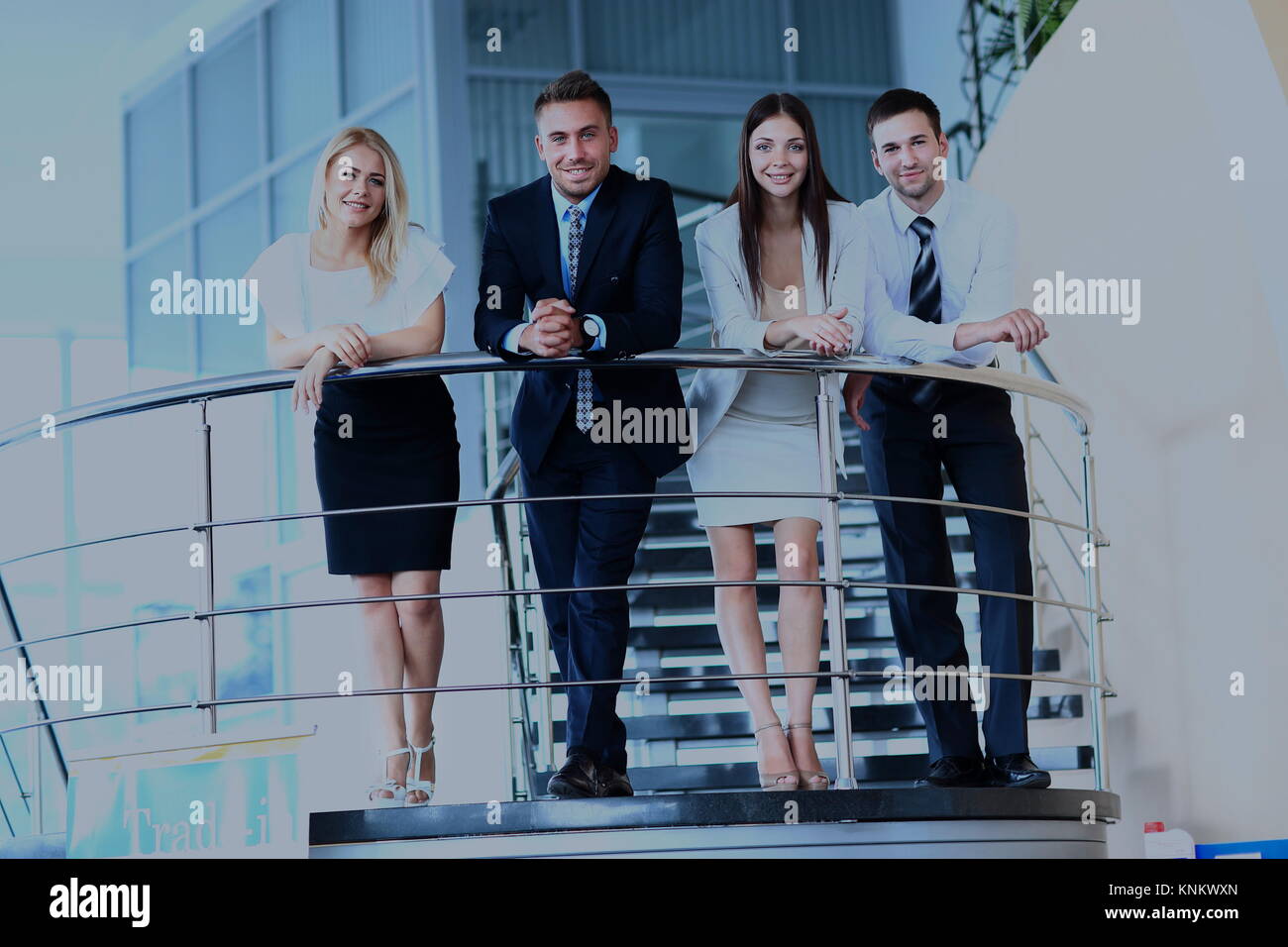 Portrait of positive business group standing on stairs of modern office ...