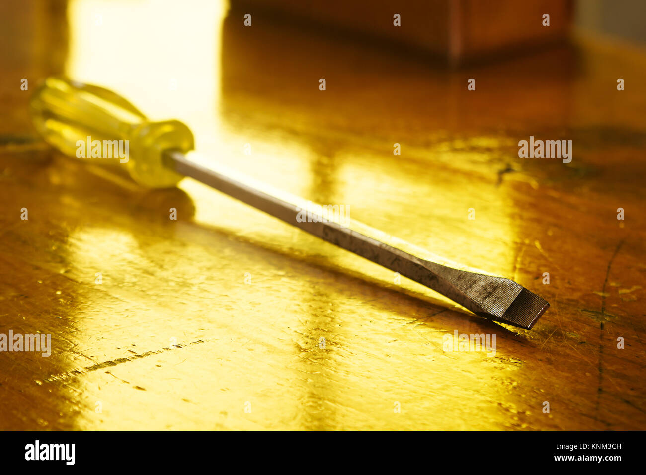 Horizontal photo of a yellow slot head screwdriver on a wood table ...