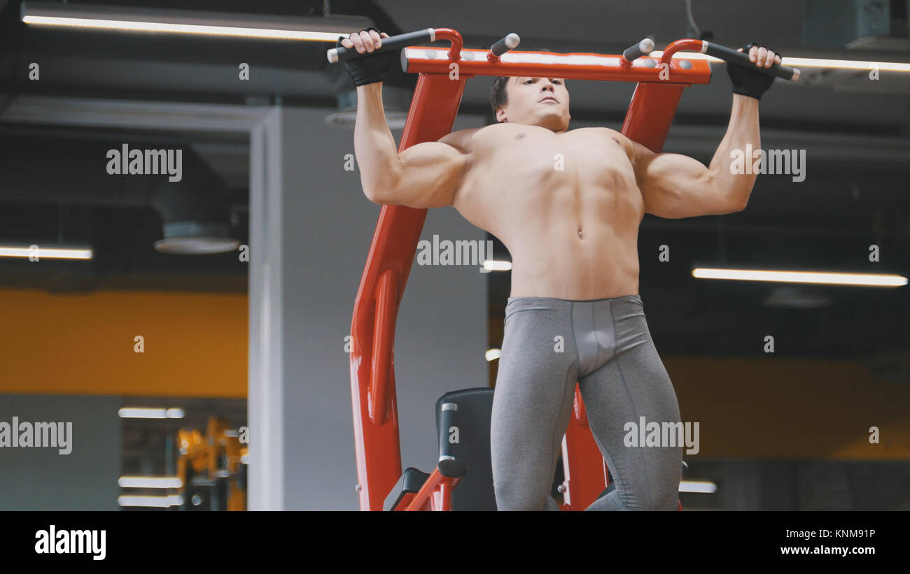 Muscular young athlete man pulling up in a gym, close up Stock Photo ...