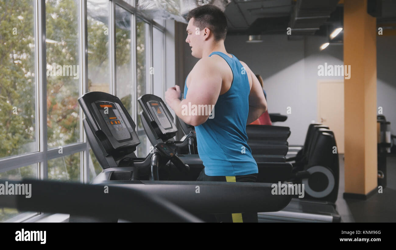 Strong man in the gym - bodybuilder running on the running track in the ...
