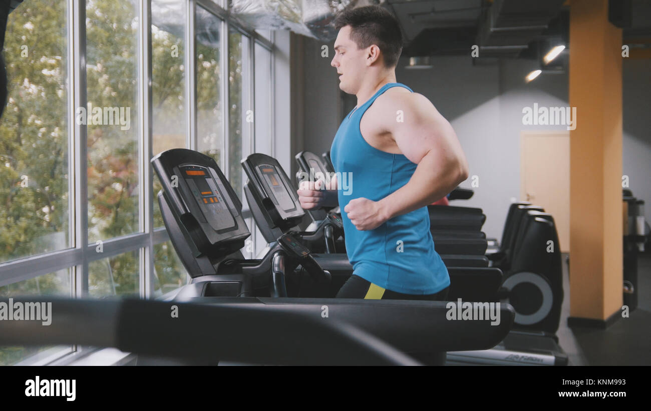 Muscular man in the gym - bodybuilder running on the running track in ...