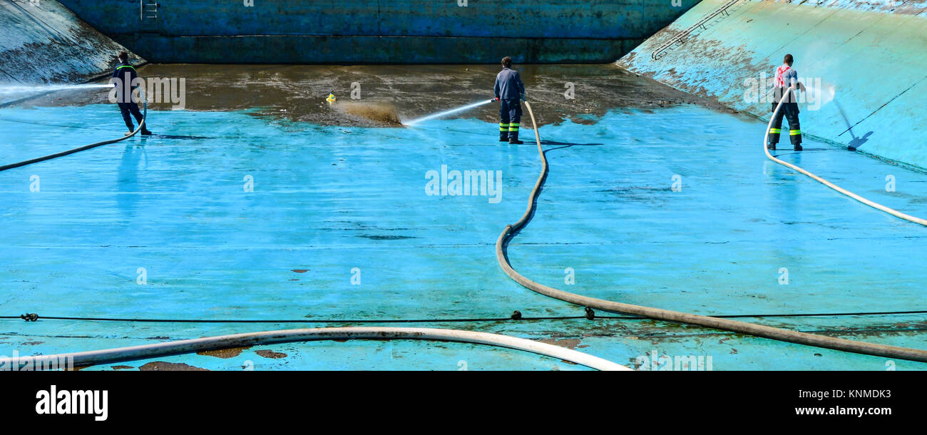 Fire hose in hand to remove the consequences of floods Stock Photo - Alamy