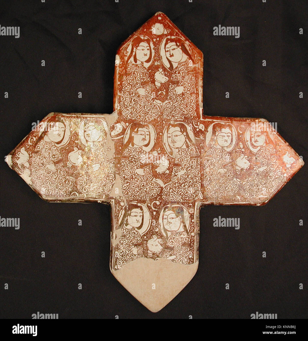 A cross-shaped ceramic tile featuring decorative motifs and ...