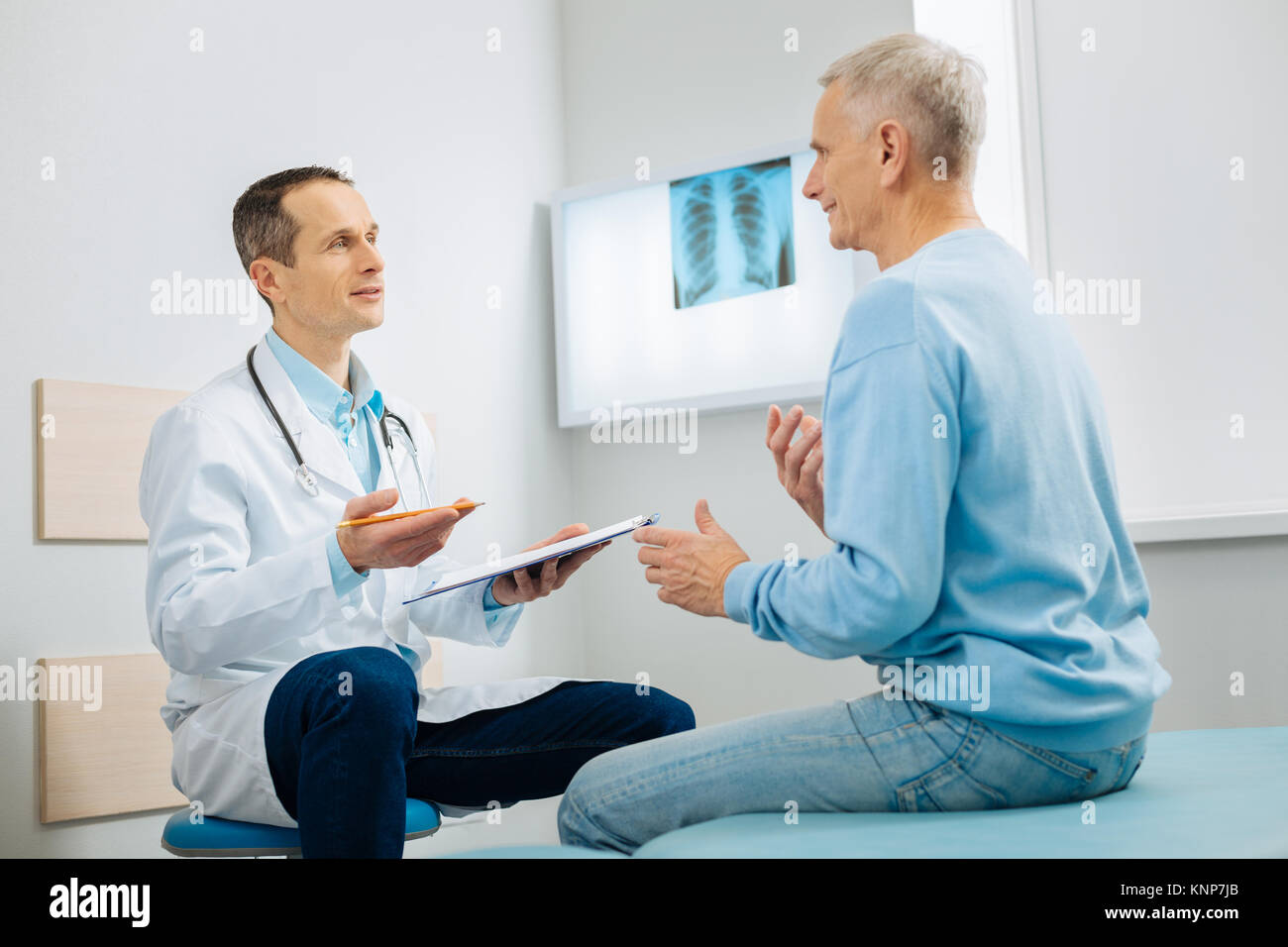 Positive doctor and patient talking to each other Stock Photo - Alamy