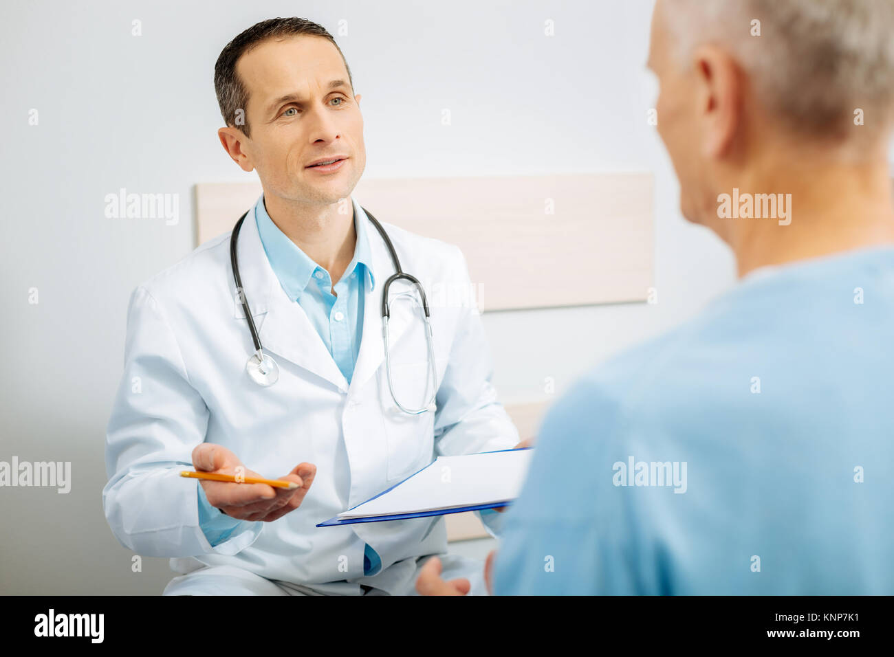 Handsome smart doctor talking to his patient Stock Photo - Alamy