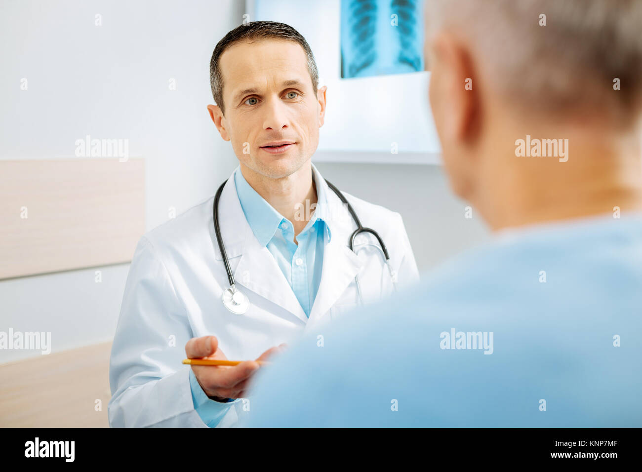 Serious experienced doctor looking at his patient Stock Photo - Alamy