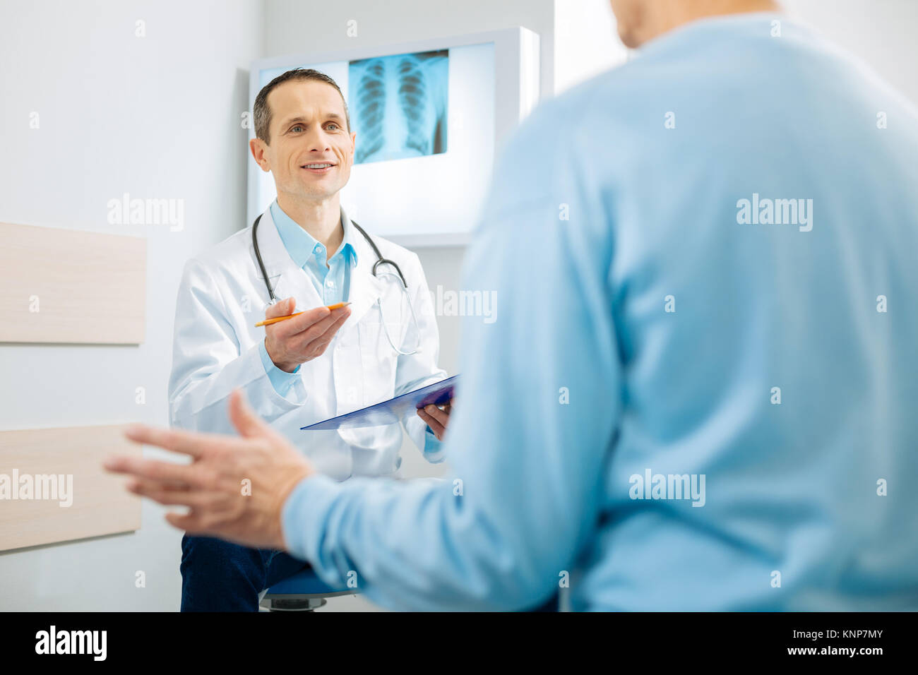 Delighted professional doctor pointing at his patient Stock Photo - Alamy