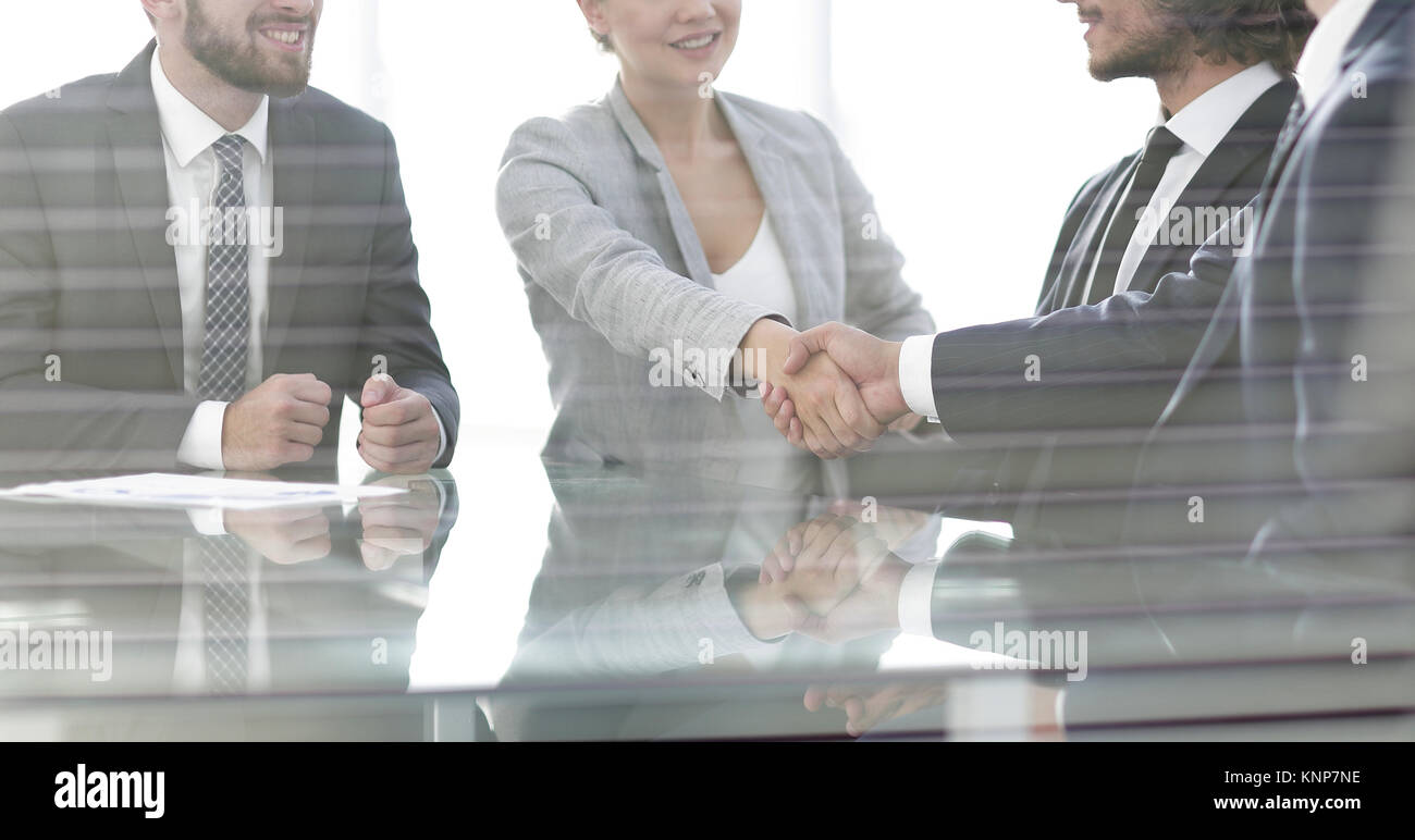 from behind the glass.handshake business people Stock Photo - Alamy