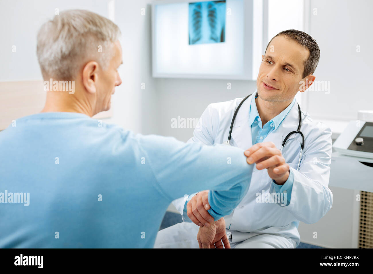 Nice professional doctor holding patients hand Stock Photo - Alamy