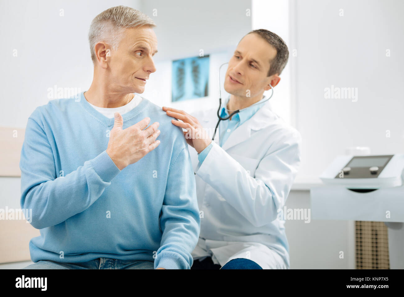Smart male doctor sitting behind his patient Stock Photo - Alamy