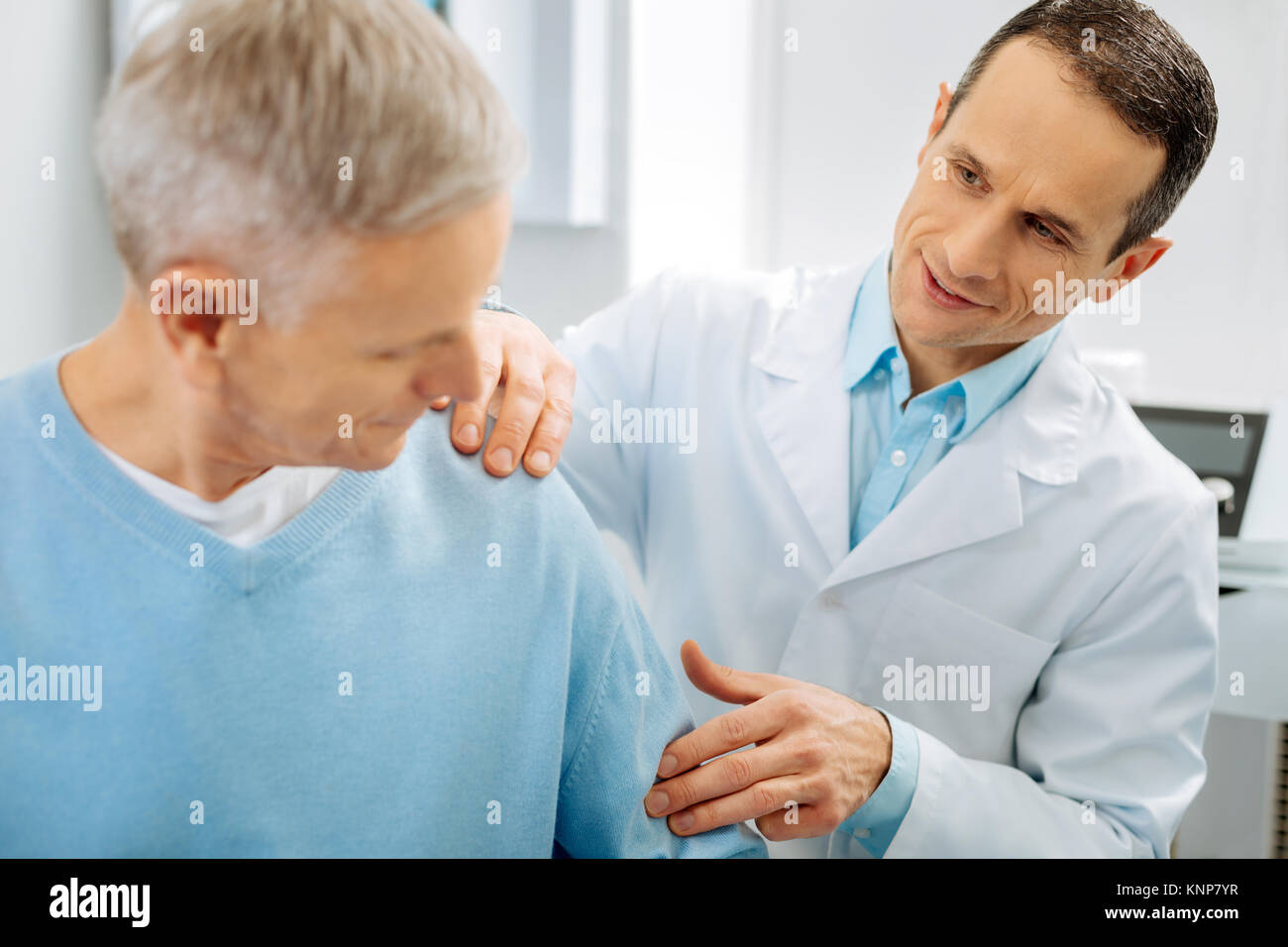 Cheerful positive doctor checking patients arm Stock Photo - Alamy