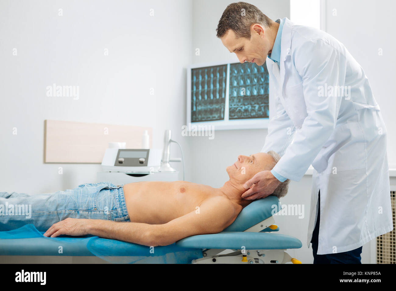 Nice serious doctor holding patients head Stock Photo - Alamy