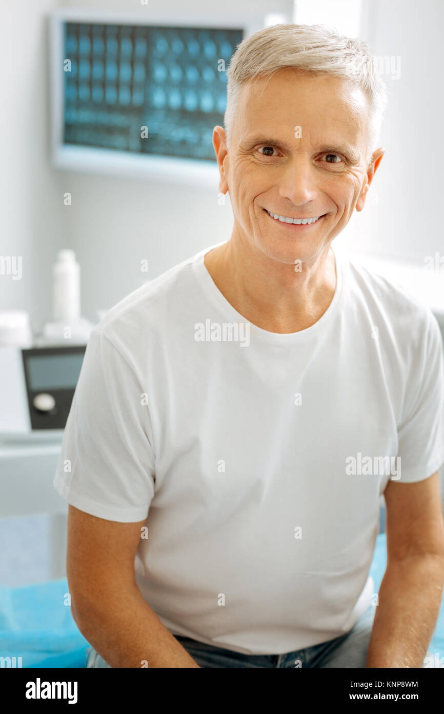 Happy delighted man sitting in the doctors office Stock Photo - Alamy