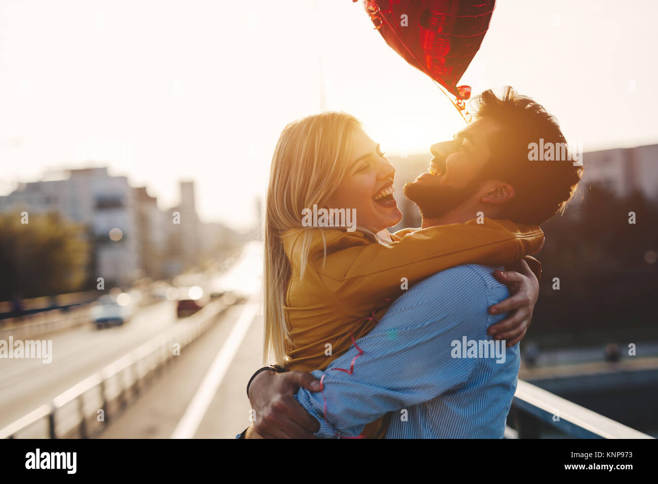 Couple in love cuddling while enjoying beautiful urban sunset together ...