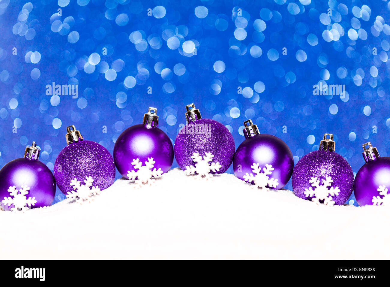 christmas purple balls in snow on blue glitter background. studio shot ...