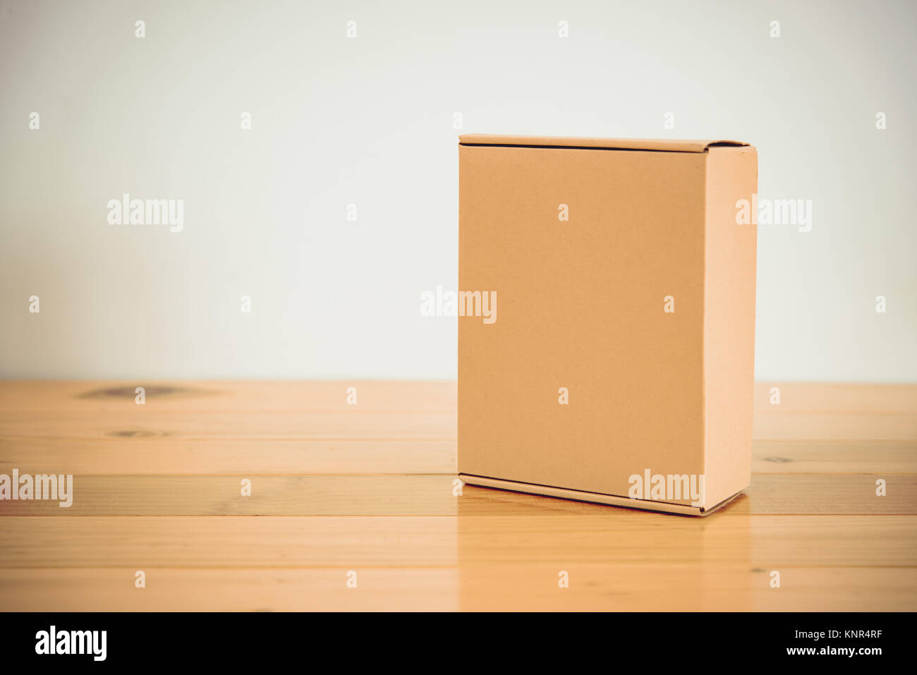 Empty brown cardboard box for mock up on bright wooden table with copy ...