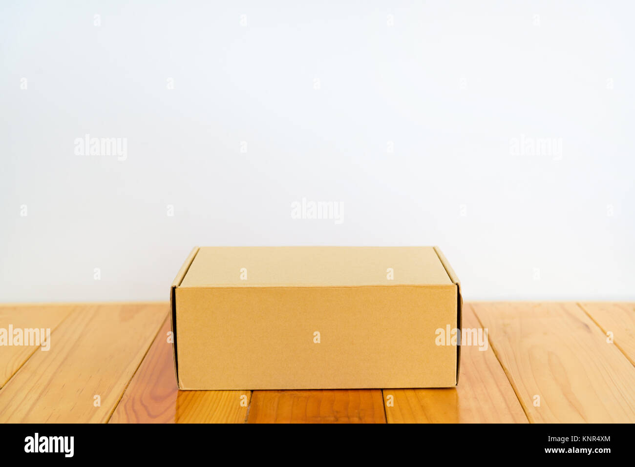 Empty brown cardboard box for mock up on bright wooden table with copy ...