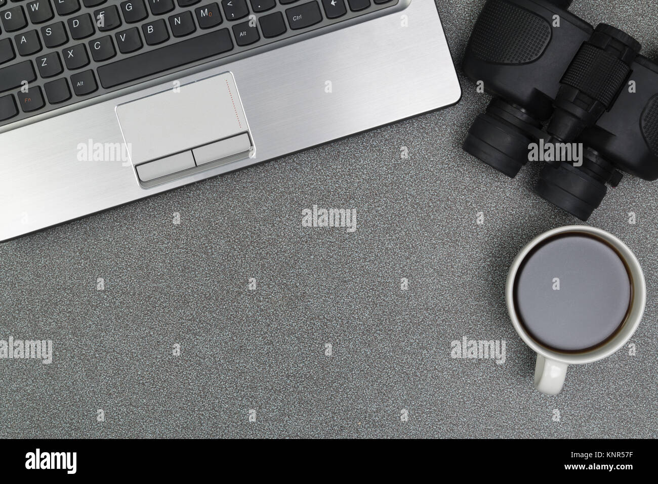 Laptop computer or notebook, binocular and cup of coffee on gray color ...