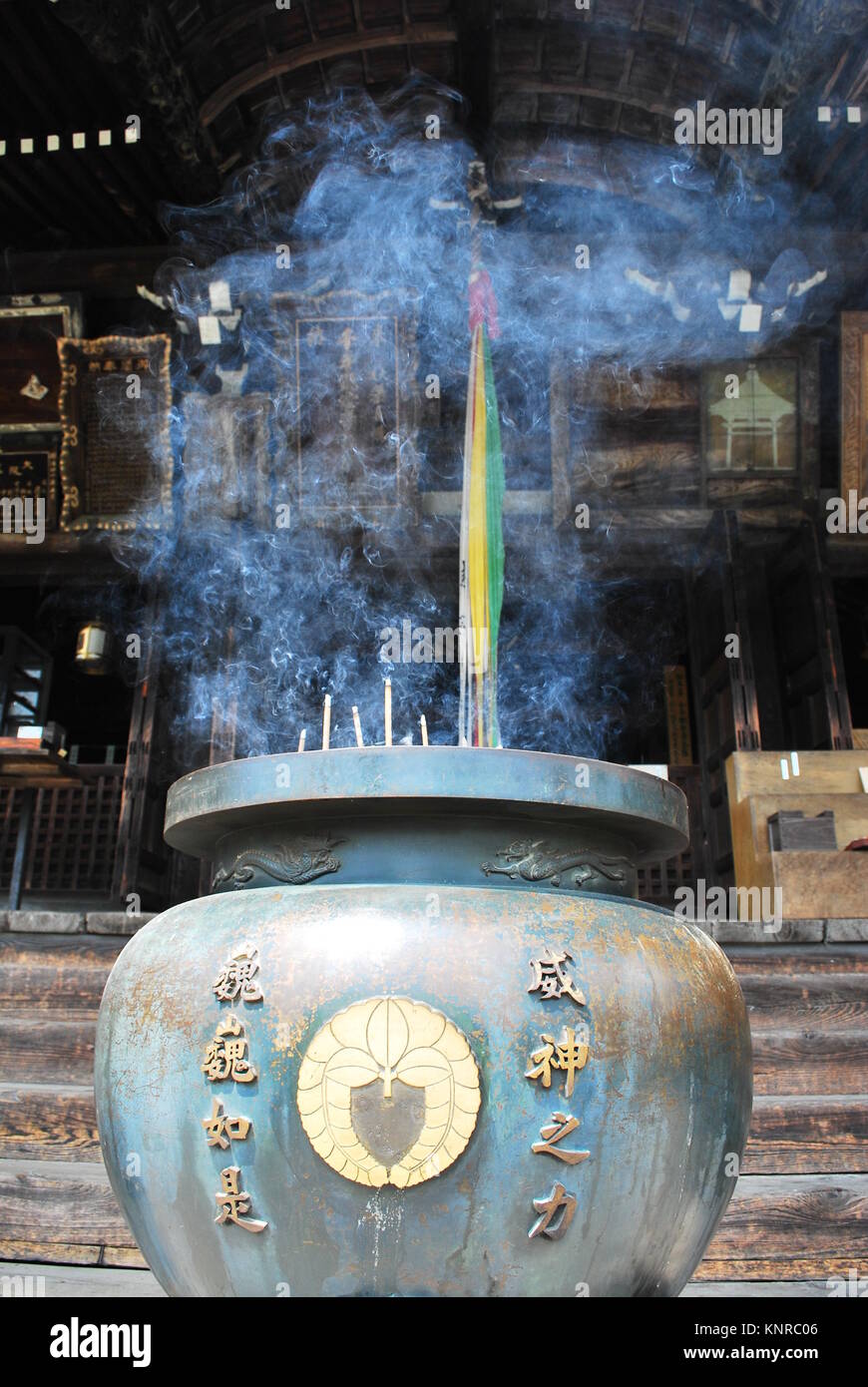 Smoke rising from joss sticks in urn in front of a temple. Symbolizes ...