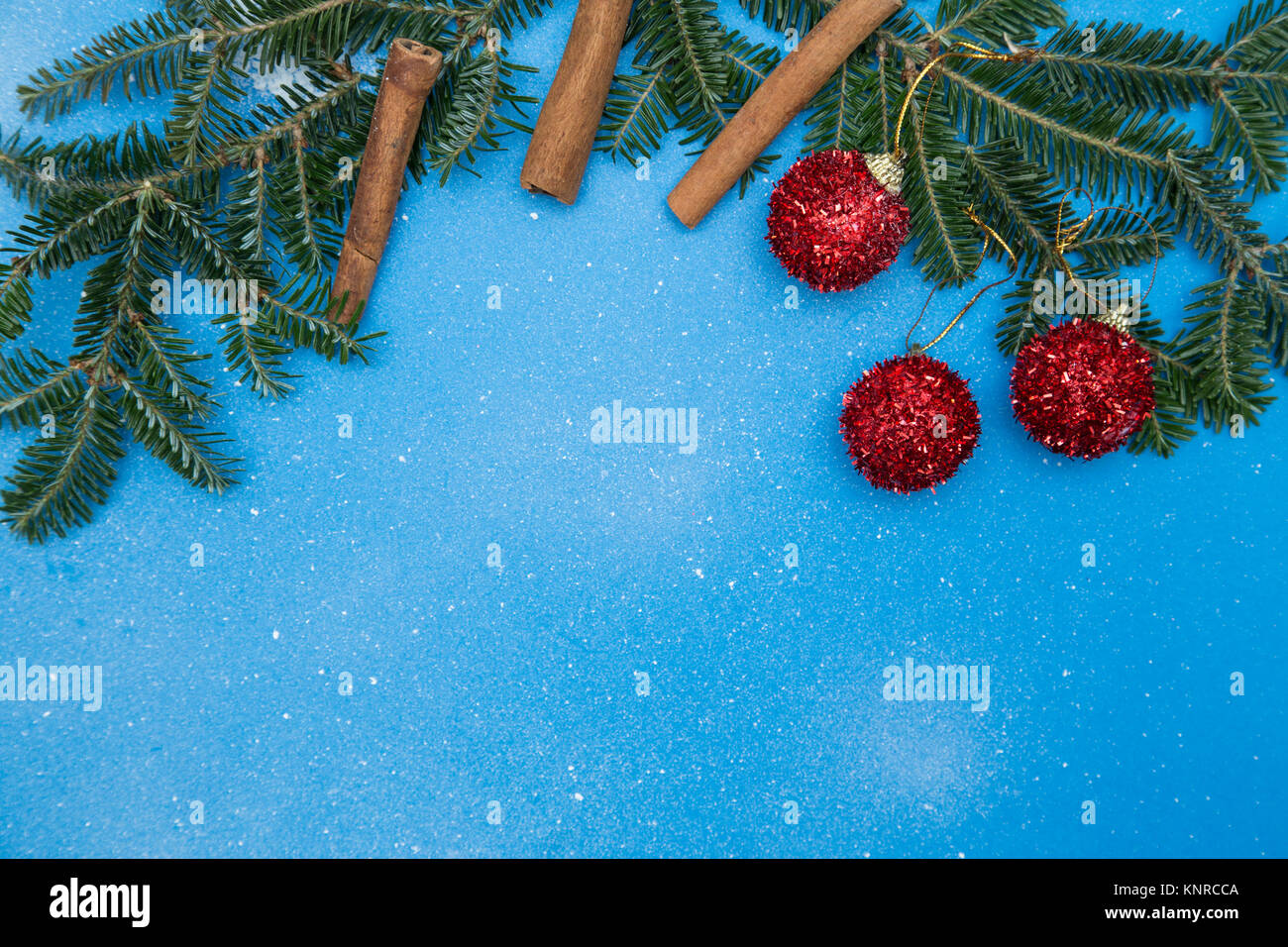Blue spotted festive background with spruce branches, glitter red balls ...