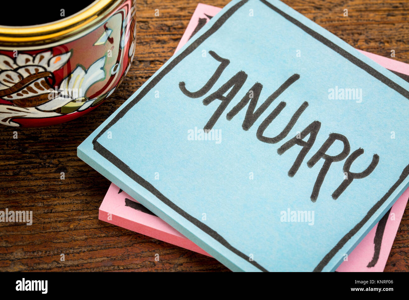 January - handwriting in black ink on a sticky note with a cup of ...