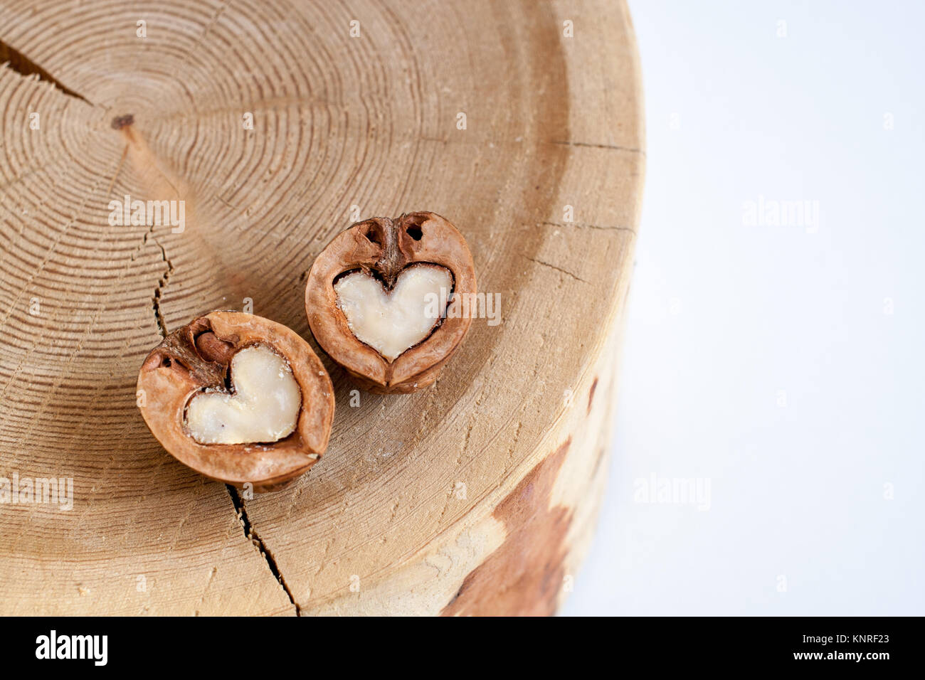 Close-up two halves of walnut in shape of heart on wooden stump on ...